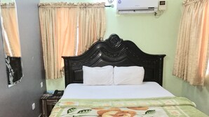 Cama com colcha florida, cabeceira preta e cortinas bege.