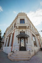 Um edifício histórico com uma entrada imponente, grandes degraus e um letreiro 'CH' bem visível.