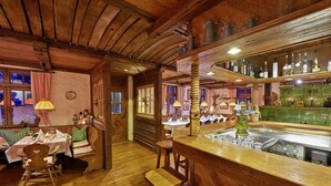 Uma área de bar rústica com móveis de madeira, balcão e prateleiras com garrafas.