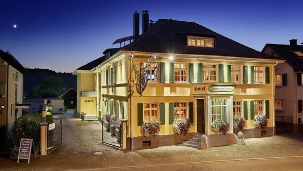 Um hotel de dois andares com estilo arquitetônico europeu tradicional, apresentando uma placa com a palavra 