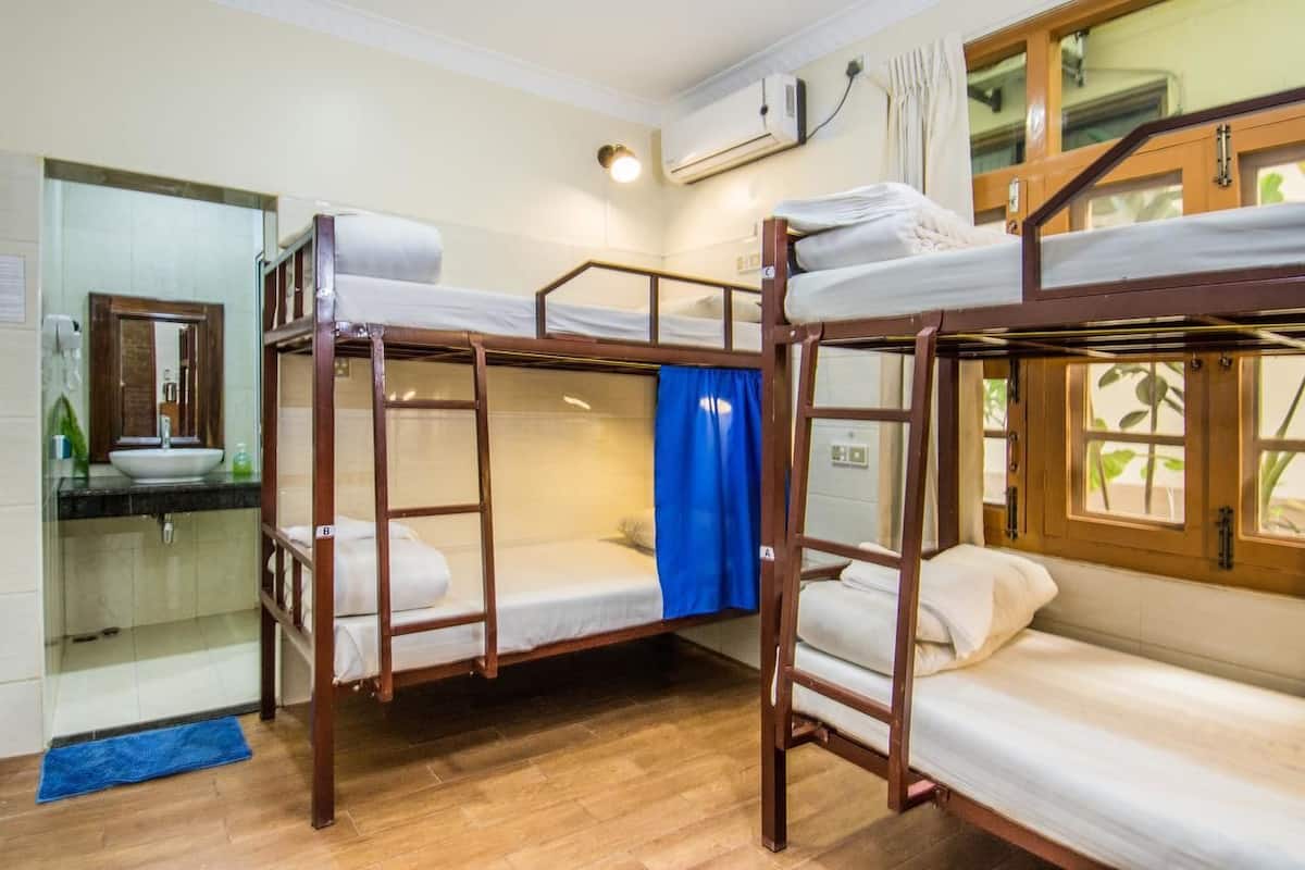 Quarto com beliches e banheiro com pia e espelho.
