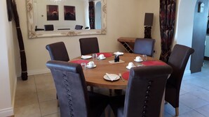 Uma sala de jantar com uma mesa redonda, seis cadeiras e um espelho grande acima.