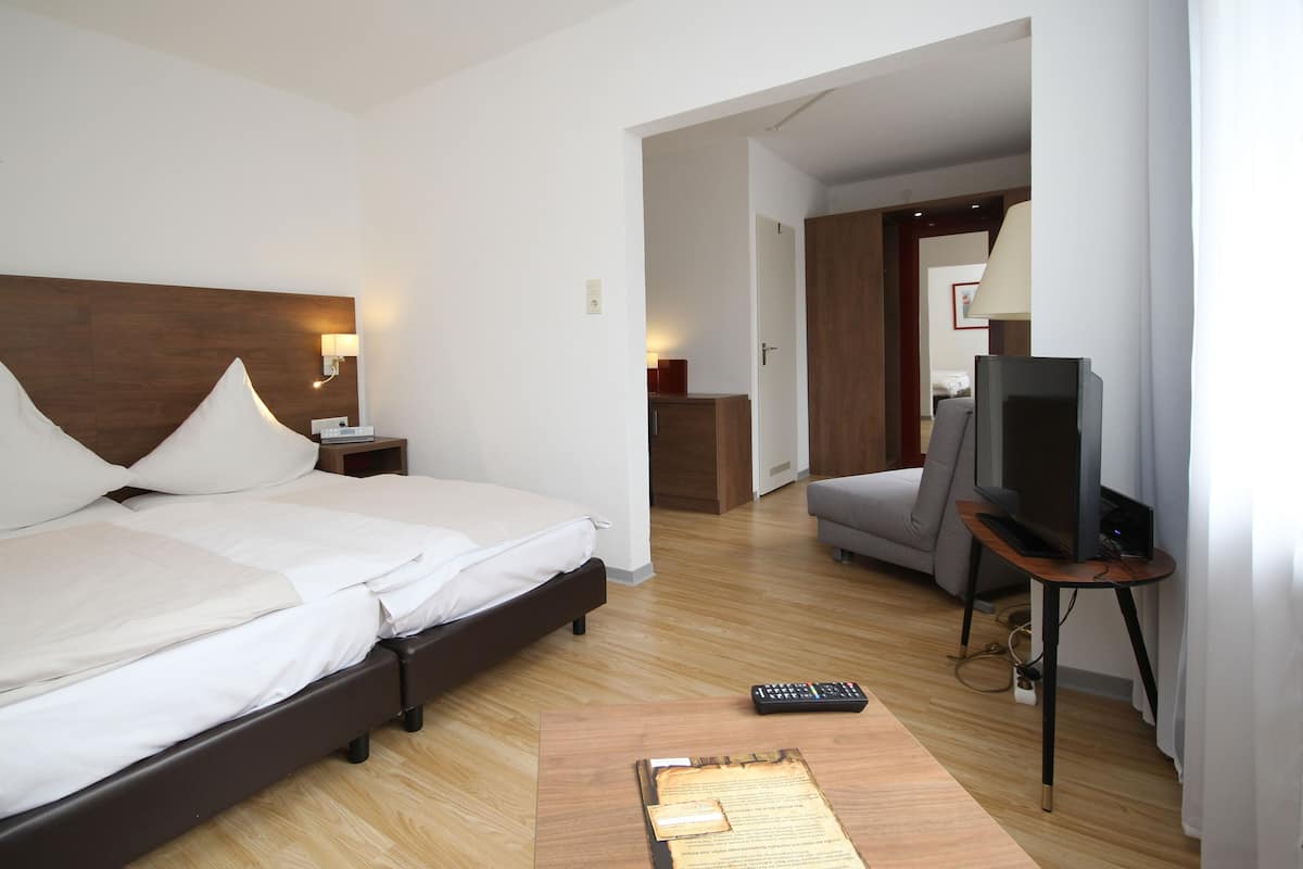 Quarto de hotel com cama, televisão, escrivaninha e cadeira.