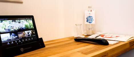 Um dispositivo Betterspace sobre uma mesa de madeira, com um controle remoto e papéis.