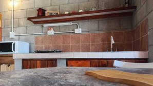 Uma cozinha com micro-ondas, pia e bancada.