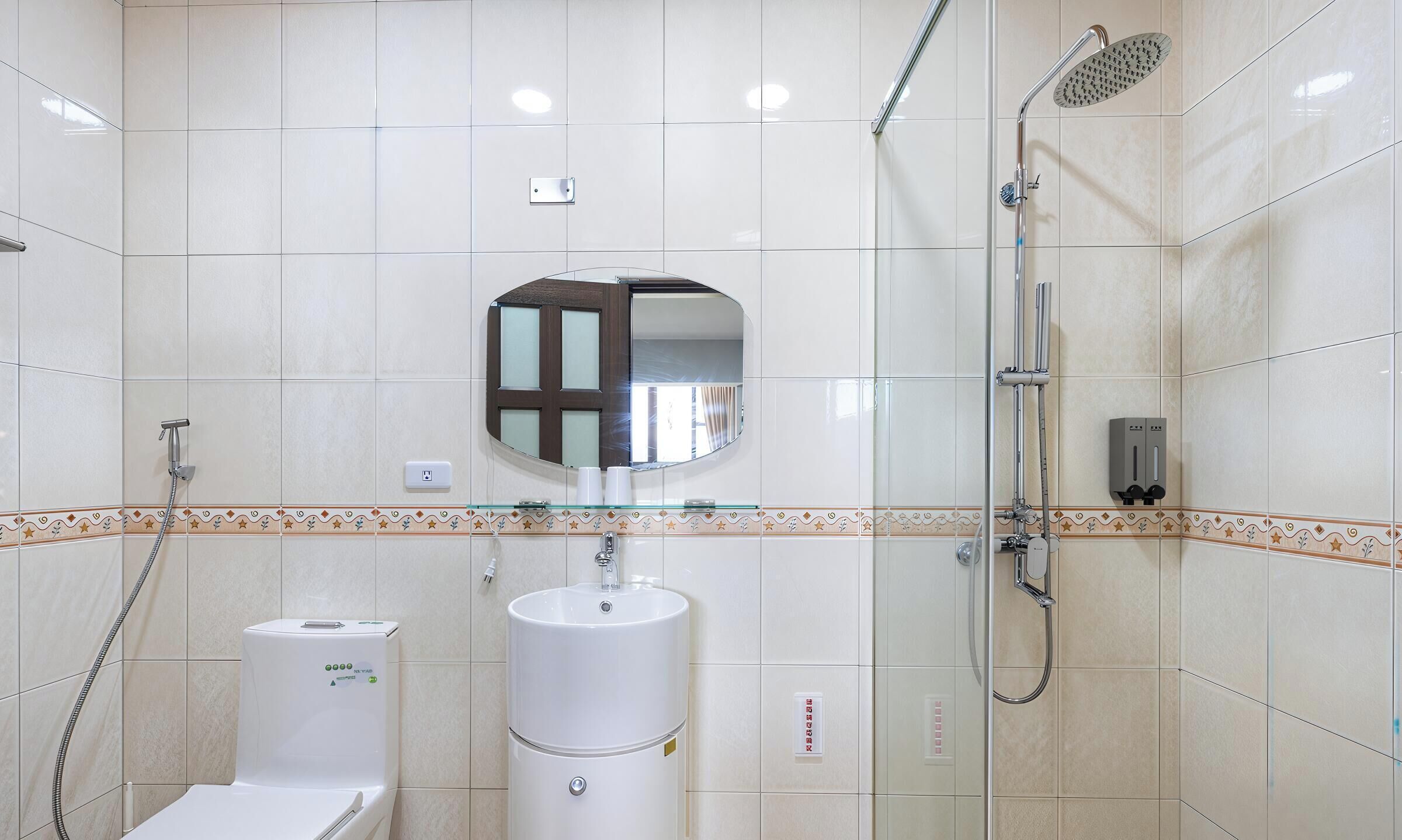 Casa de banho com sanita, lavatório, espelho, chuveiro e porta-toalhas.