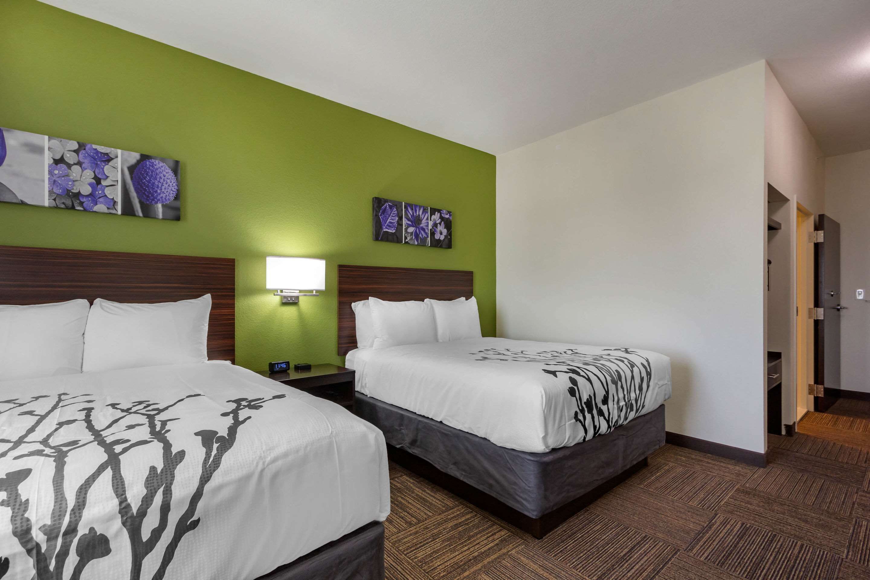 Quarto de hotel com duas camas, paredes verdes e obras de arte na parede.