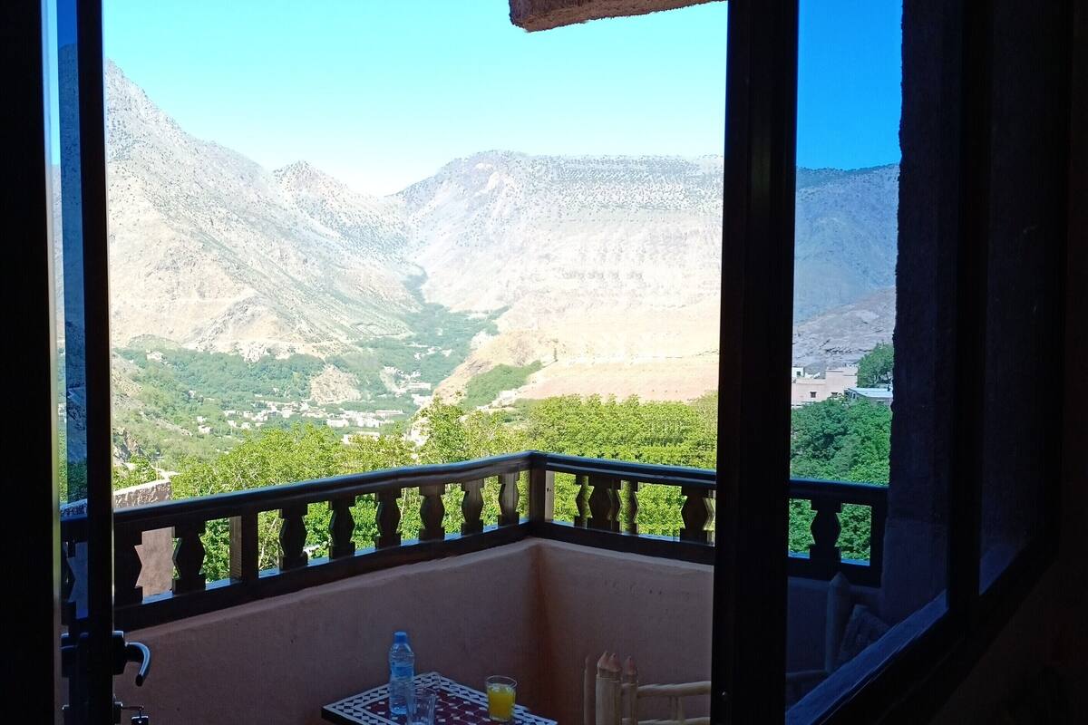 Varanda com mesa e cadeiras, com vista para uma paisagem montanhosa.