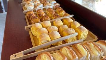 Um buffet com diversos produtos de panificação, incluindo pães e doces, expostos em tábuas de madeira.