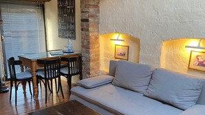 Uma sala de estar acolhedora com uma mesa de centro de madeira, um sofá cinza claro e um espaço de jantar com mesa e cadeiras.