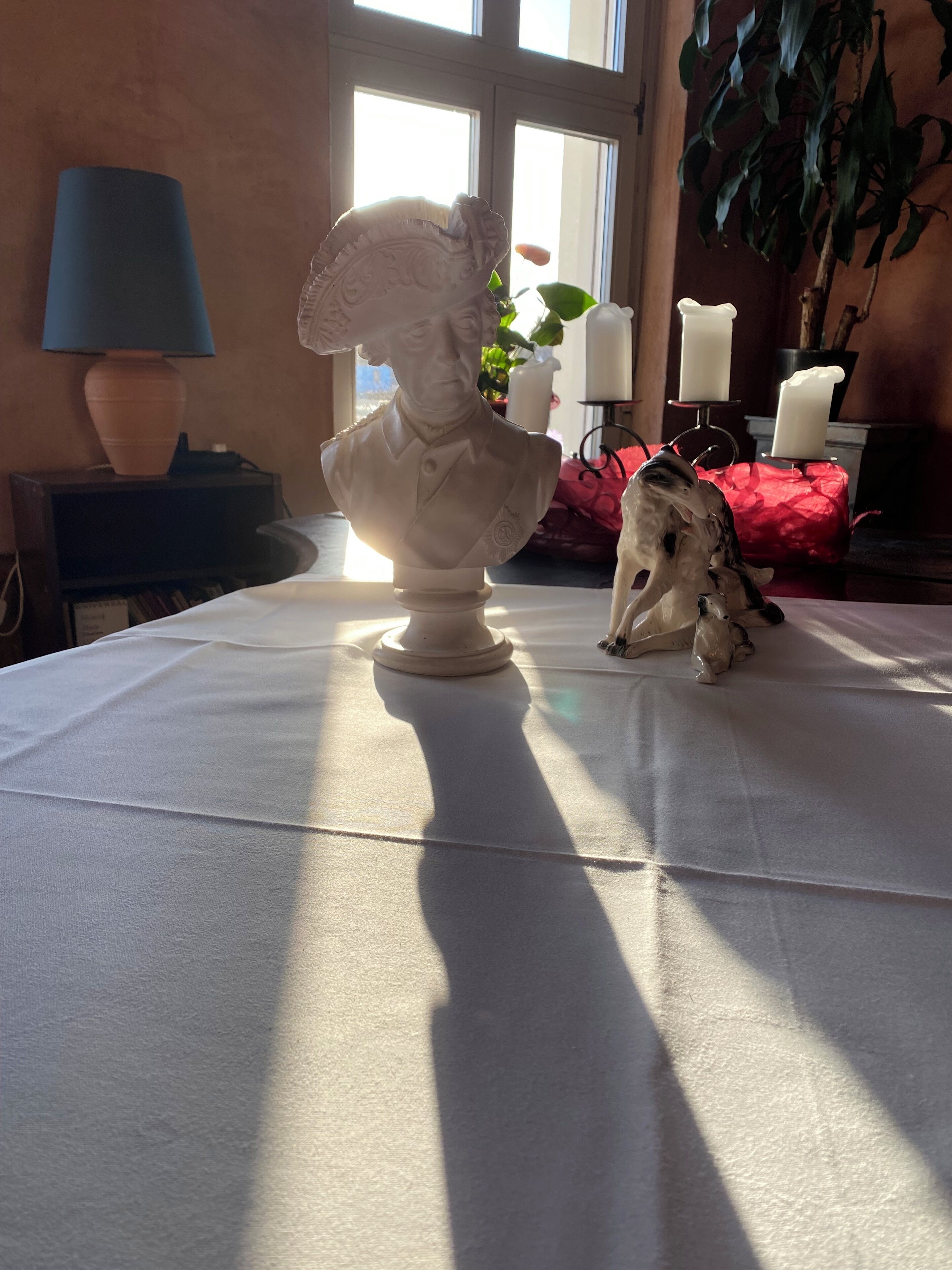 Quarto com uma mesa que apresenta uma estátua em busto, uma pequena figura e uma luminária.