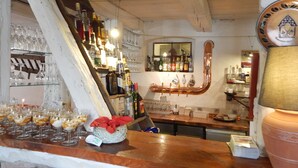 Uma área de bar com prateleiras de garrafas, copos e um cano de cobre.
