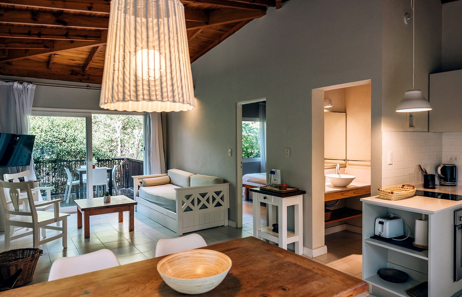 Um interior moderno com área de jantar, sofá, cozinha e vista para o exterior.