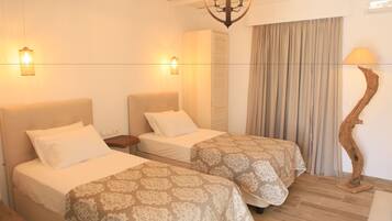 Quarto de hotel com duas camas, um candelabro, uma mesa de cabeceira, um abajur e uma escultura em madeira.