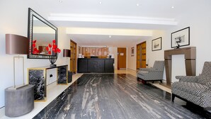 Um hall de hotel moderno com balcão de recepção, área de estar e um espelho grande.