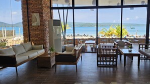 Ampla área de estar coberta, com vista para a praia e o oceano.
