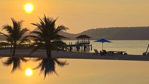 Uma praia com palmeiras, um píer e cadeiras de praia.