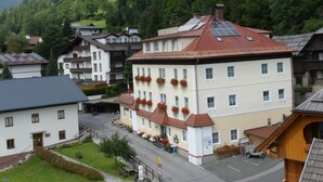 Um edifício de vários andares com telhado de telhas vermelhas, painéis solares e caixas de flores nas janelas.