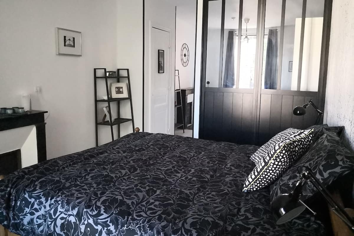 Quarto com cama, escrivaninha, prateleira e porta.