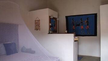 Quarto com cama, mesa de cabeceira, espelho e um quadro na parede.