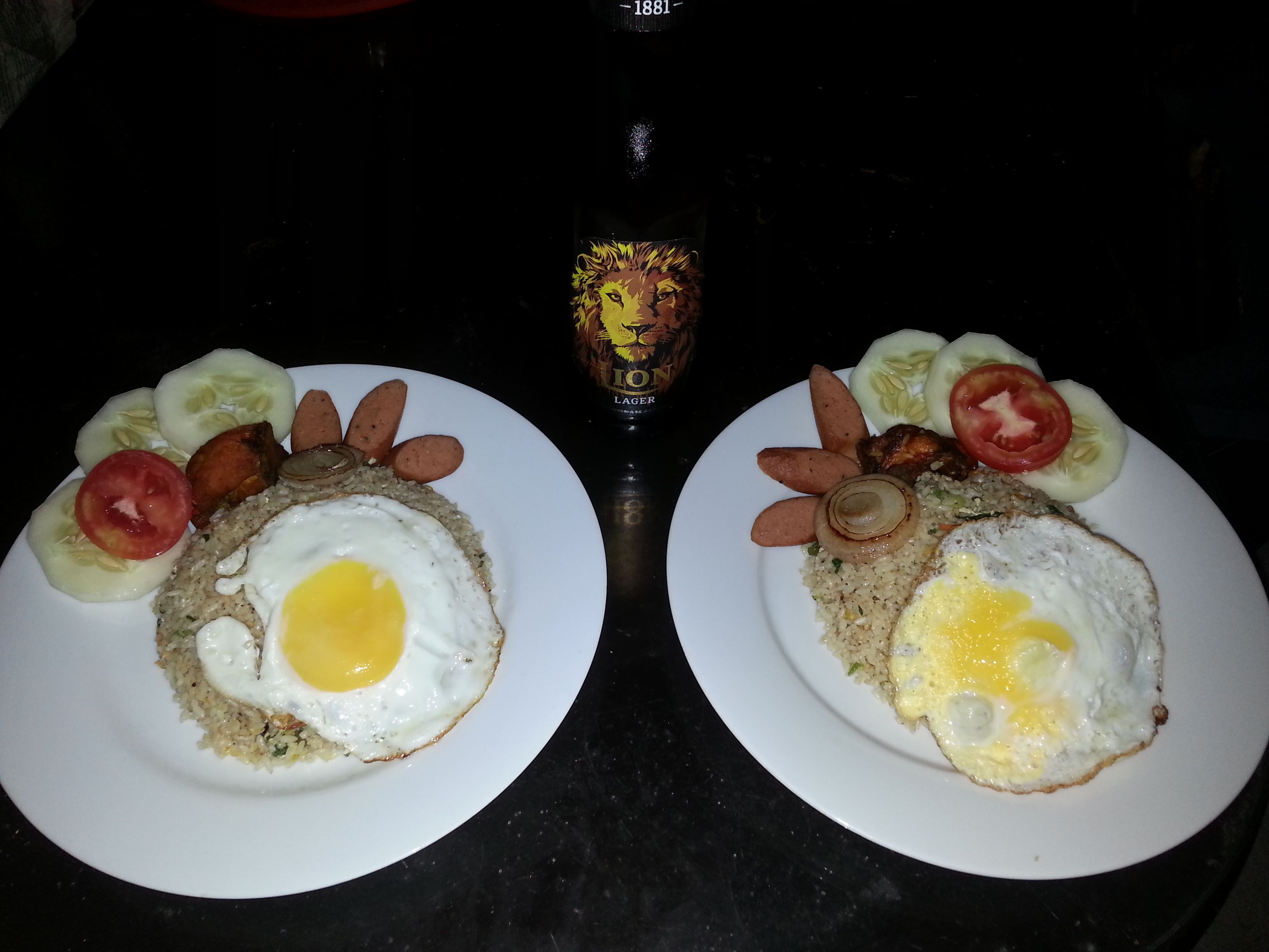 Duas travessas de comida com uma garrafa ao fundo.