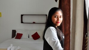 Quarto de hotel com uma cama, um travesseiro vermelho, um travesseiro branco e um cobertor vermelho sobre a cama.
