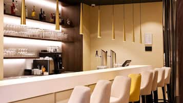 Uma área de bar com um balcão comprido, vários banquinhos e luminárias pendentes.