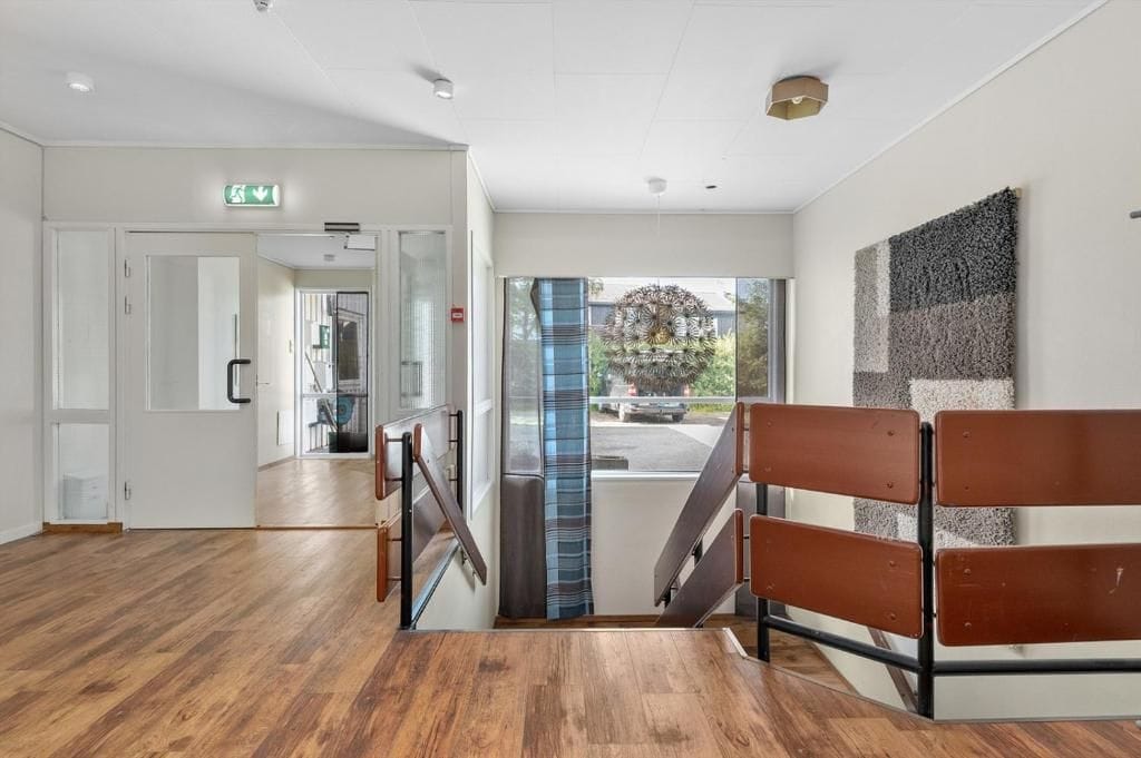 Um interior moderno com piso de madeira, uma escada e vista pela janela.