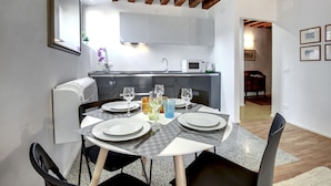 Uma área de refeições com uma mesa posta para quatro pessoas, um micro-ondas e uma pia ao fundo.