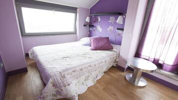 Um quarto com uma cama, uma mesa redonda e uma janela com cortinas.