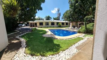 Um imóvel residencial com piscina, varanda coberta e gramado bem cuidado.