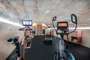 Uma academia moderna com esteiras, bicicletas ergométricas e uma tela de televisão.