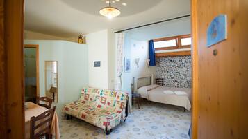 Um quarto com cama, sofá, mesa de jantar com cadeiras e uma pequena mesa com uma cadeira.
