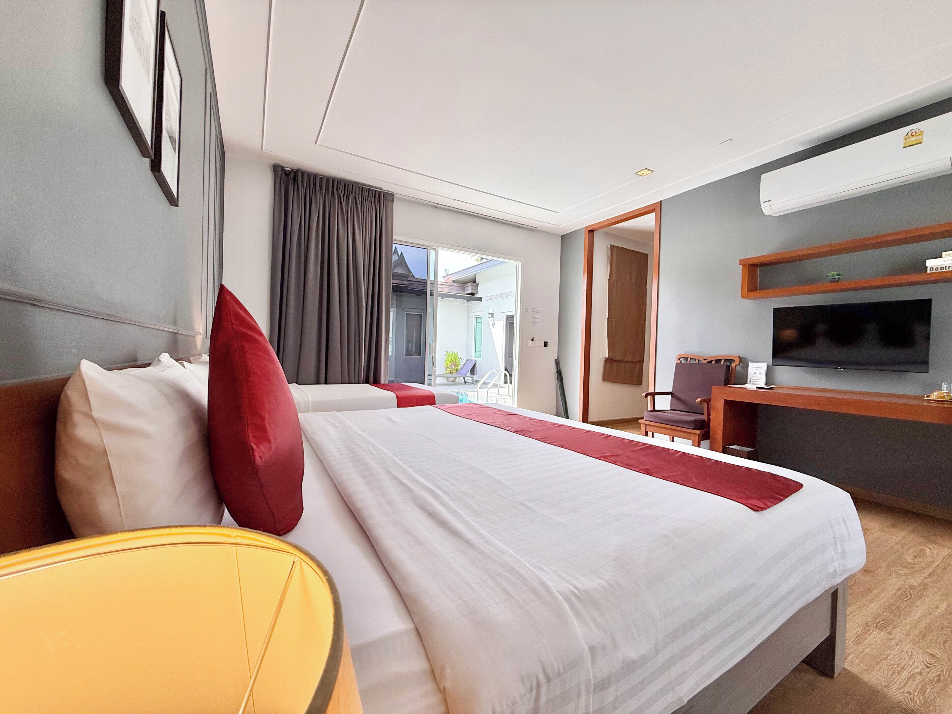 Quarto de hotel com cama, escrivaninha, televisão e janela com cortinas.