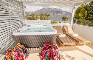 Terraço no telhado com banheira de hidromassagem, espreguiçadeiras e guarda-sóis coloridos.