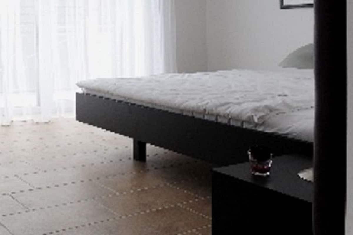 Um quarto com uma cama, uma mesa de cabeceira e uma janela com cortinas.