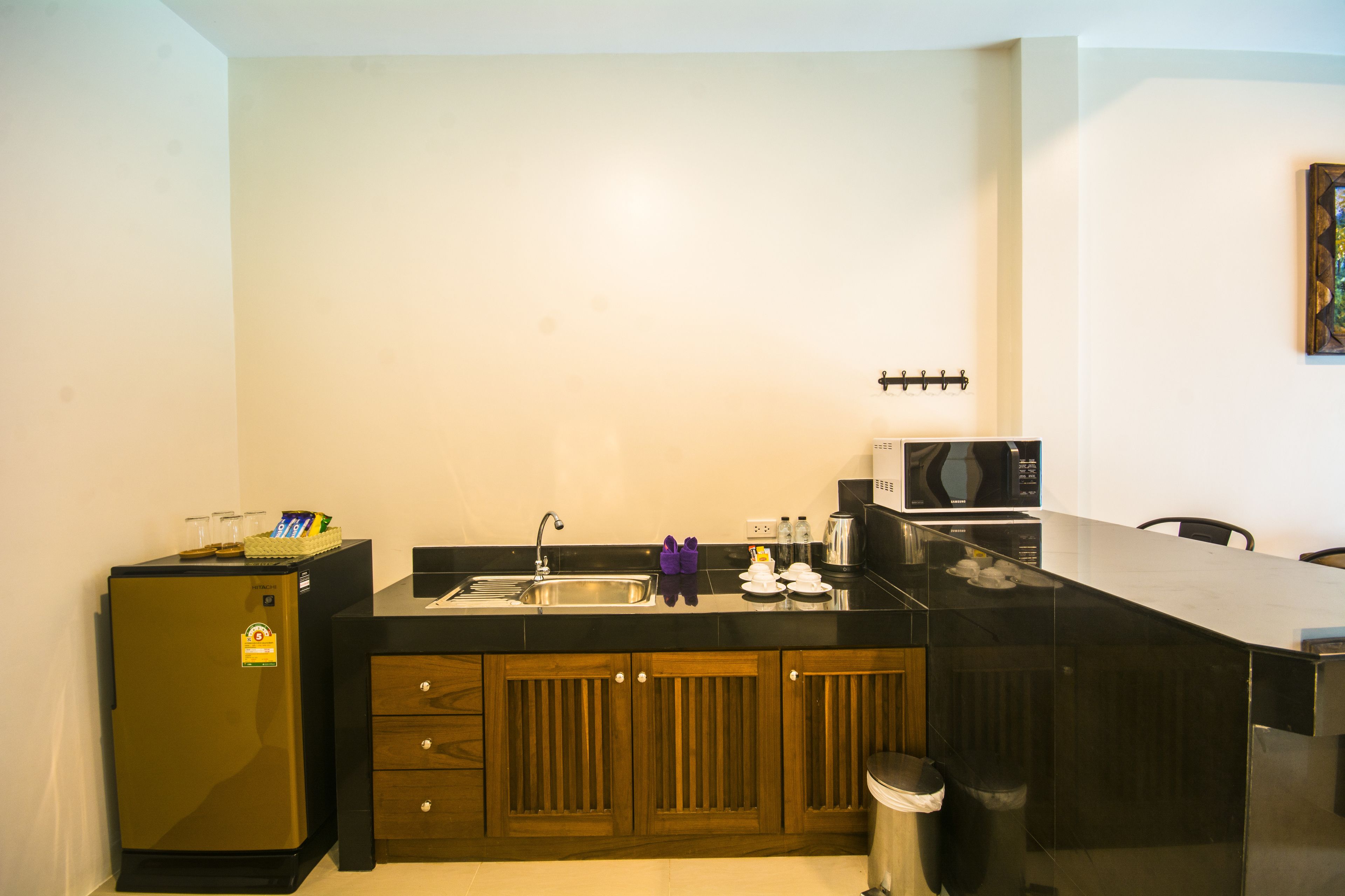 Cozinha compacta com geladeira, pia, micro-ondas e armários de madeira.