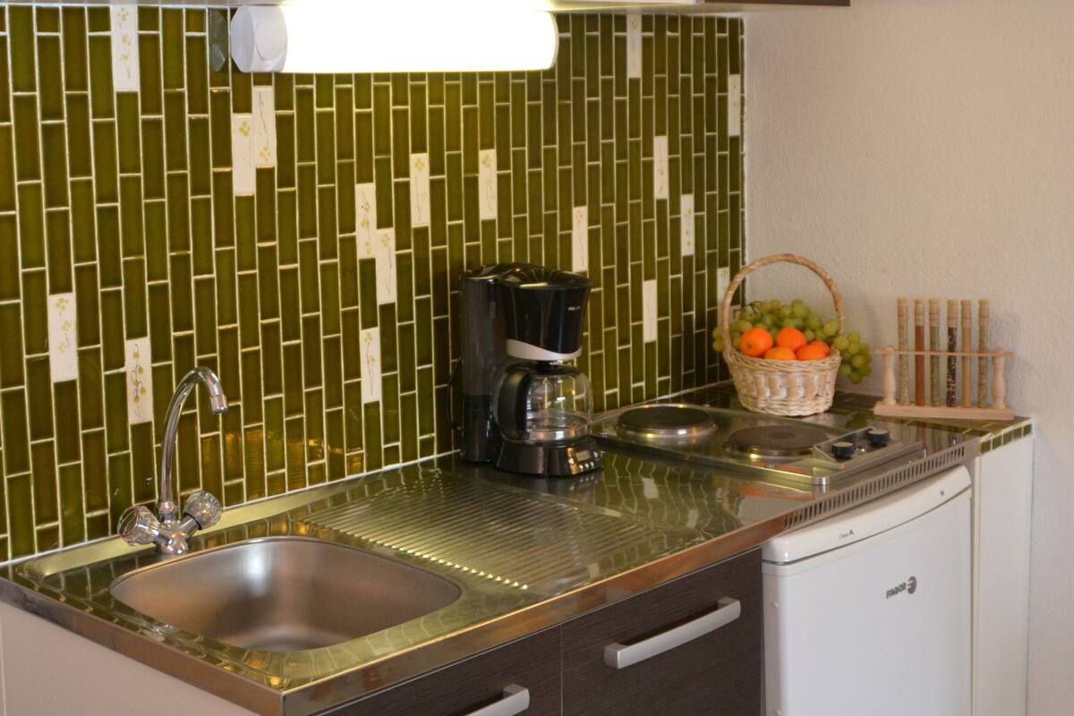 Uma cozinha compacta com micro-ondas, cafeteira e uma pia pequena.
