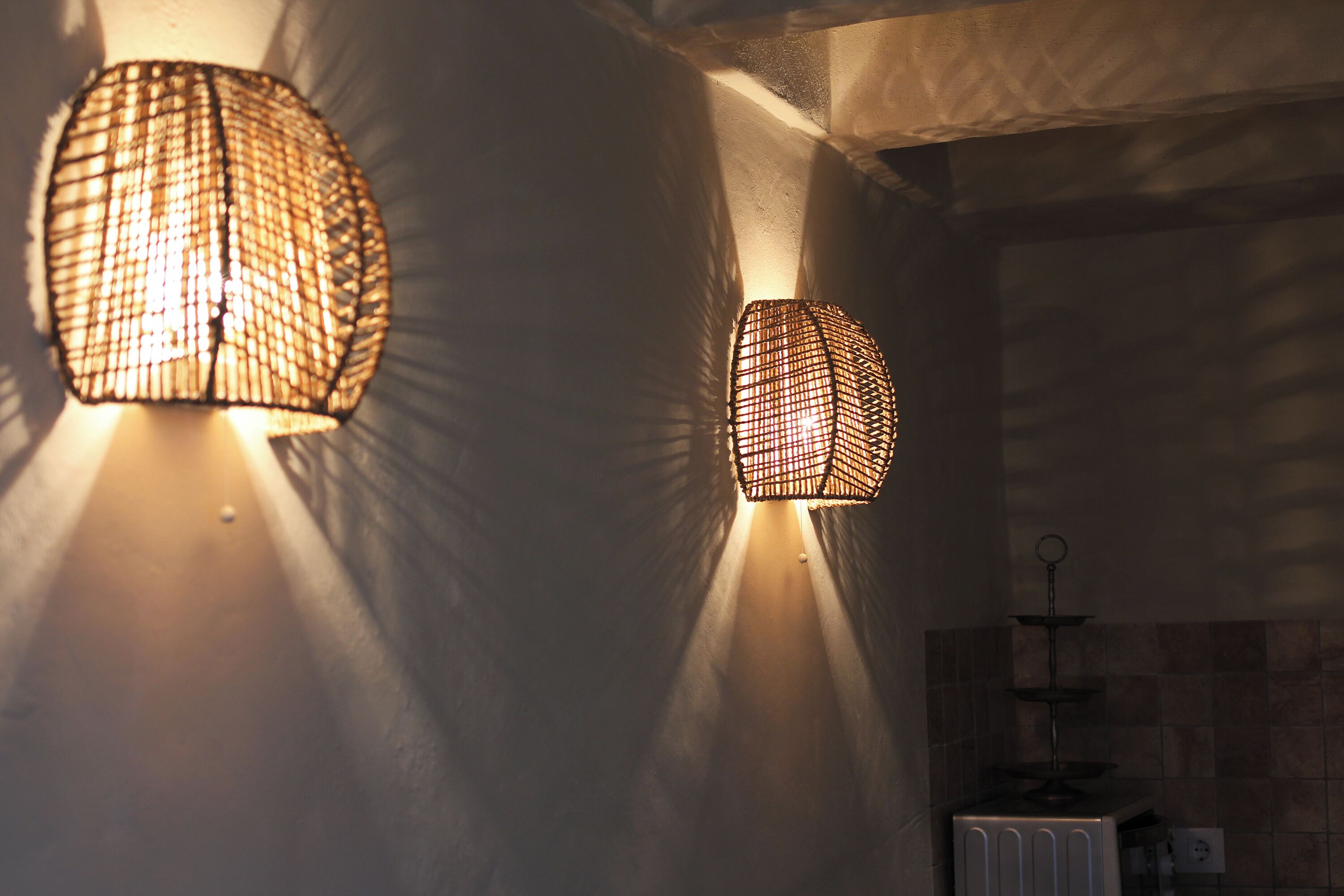 Casa de banho com duas luminárias de parede com textura, projetando sombras na parede.