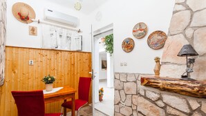 Uma área de refeições com uma mesa de madeira e cadeiras vermelhas, uma parede de pedra e pratos decorativos na parede.
