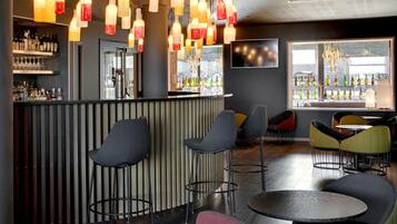Uma área de bar moderna com balcão, banquetas e luminárias pendentes.