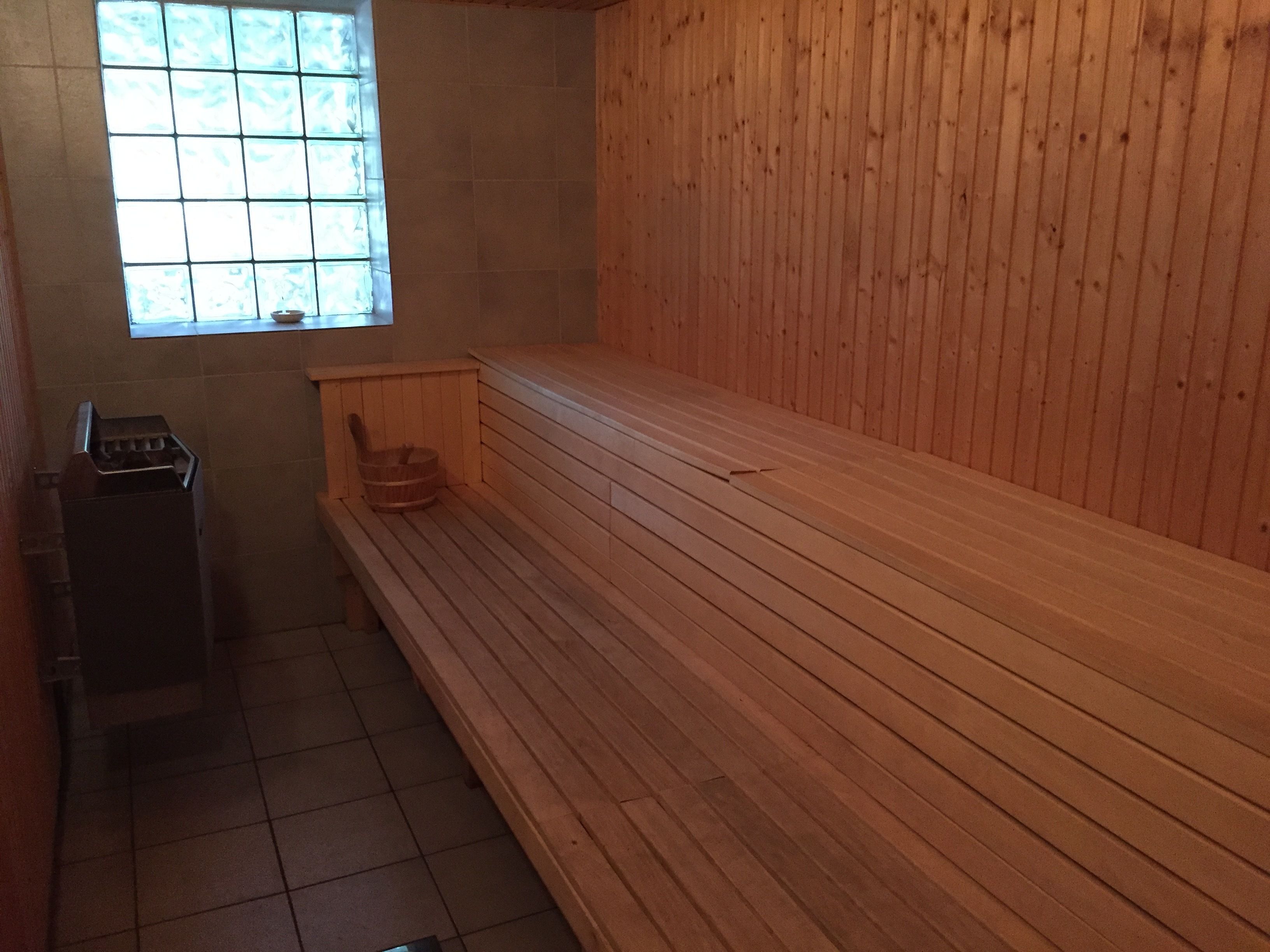 Uma sala de sauna com bancos de madeira, uma pequena janela e piso revestido de azulejos.