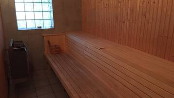 Uma sala de sauna com bancos de madeira, uma pequena janela e piso revestido de azulejos.