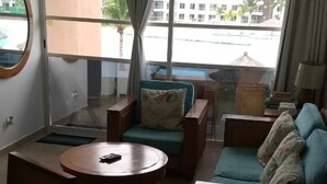 Quarto de hotel com área de estar, incluindo uma mesa redonda, dois sofás e uma janela com cortinas.