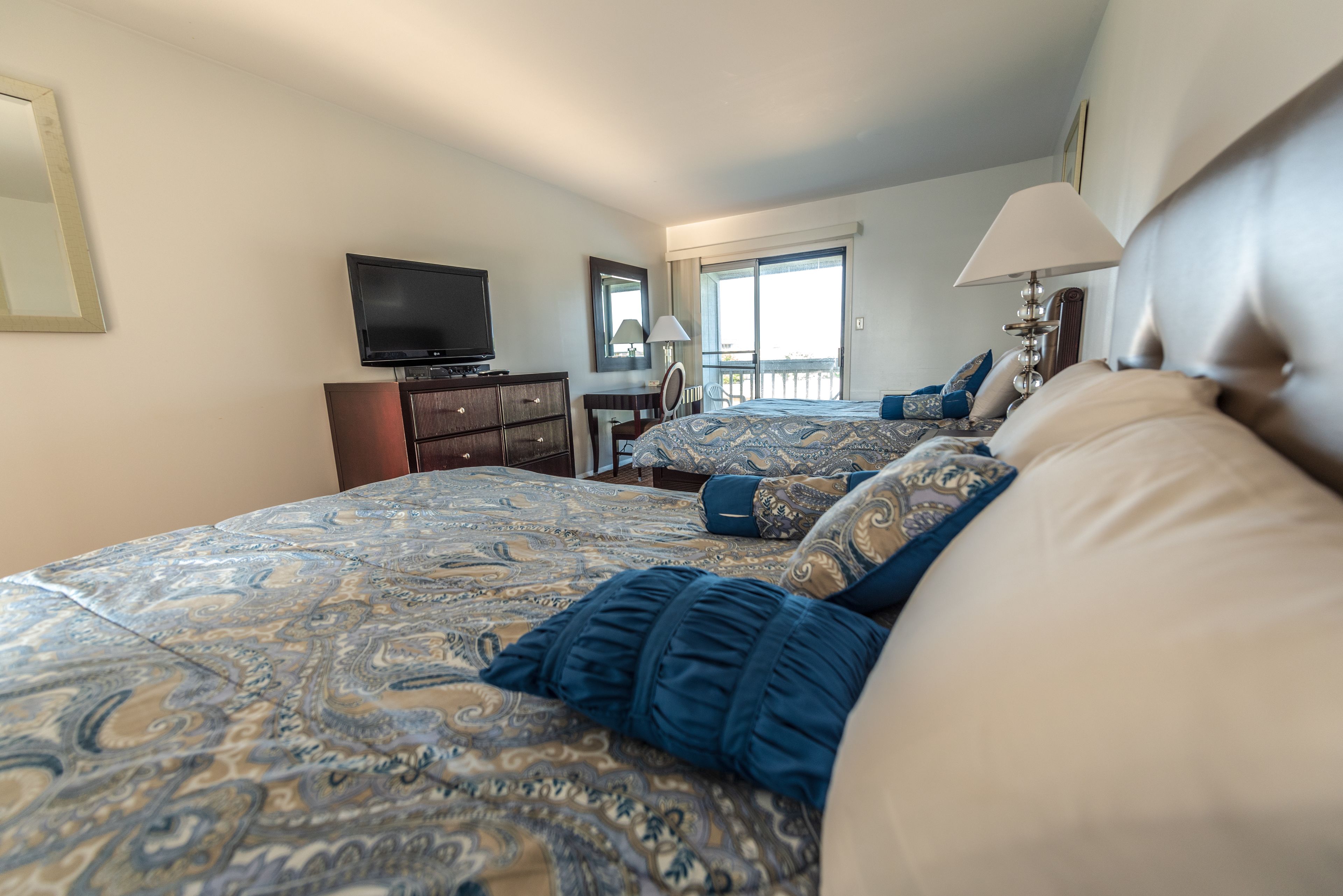 Quarto de hotel com duas camas, televisão, escrivaninha e janela.