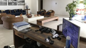 Uma sala de estar moderna com uma escrivaninha de madeira, dois sofás, uma mesa de centro e um vaso com planta.