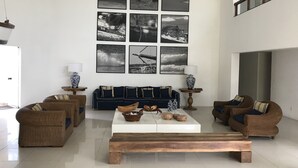 Uma sala de estar espaçosa com uma parede grande de fotografias a preto e branco, dois sofás, uma mesa de centro e um banco de madeira.