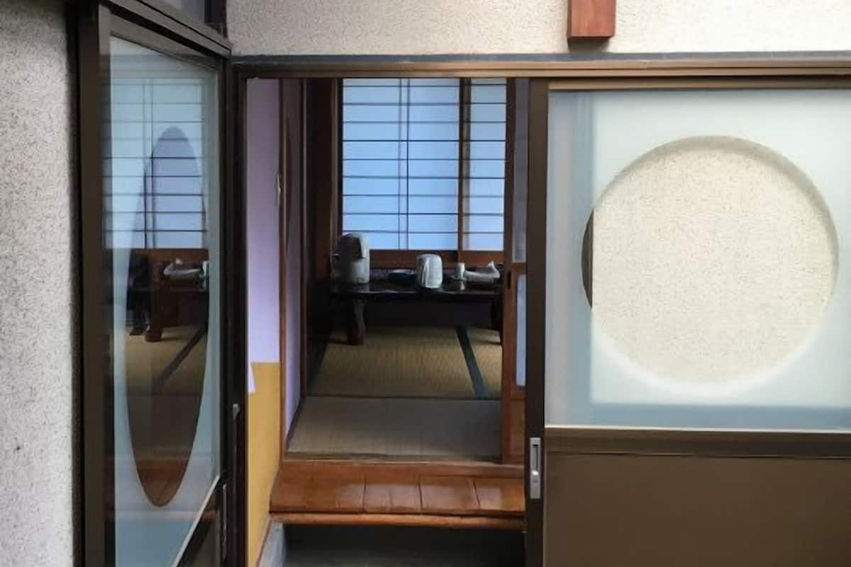 Um quarto japonês tradicional com portas deslizantes, piso de tatame e vista para o exterior.