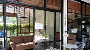 Um interior moderno com porta de vidro, sofá de couro marrom e cadeiras de metal branco.