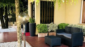 Uma área de pátio com mobiliário de jardim, um poste de luz e plantas em vasos.
